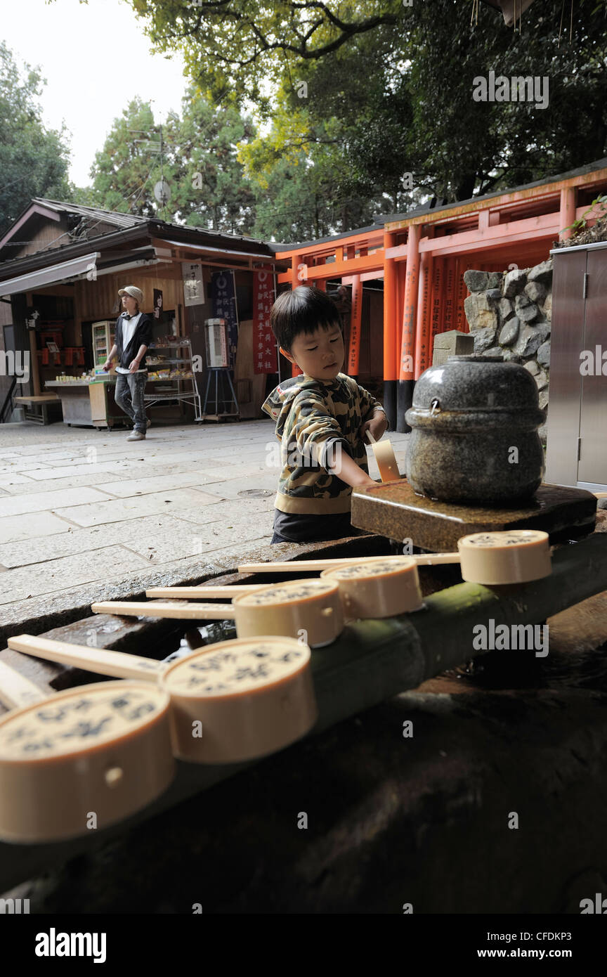 little Japanese boy doing purification rite at Fushimi Inari Shrine ...