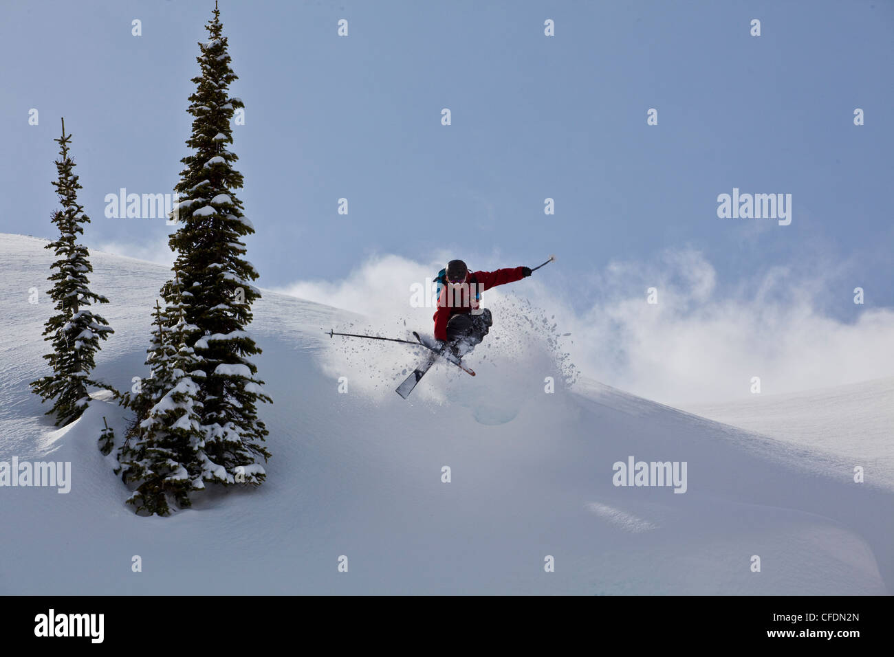 A male skier catches some air into fresh powder while ski touring at ...
