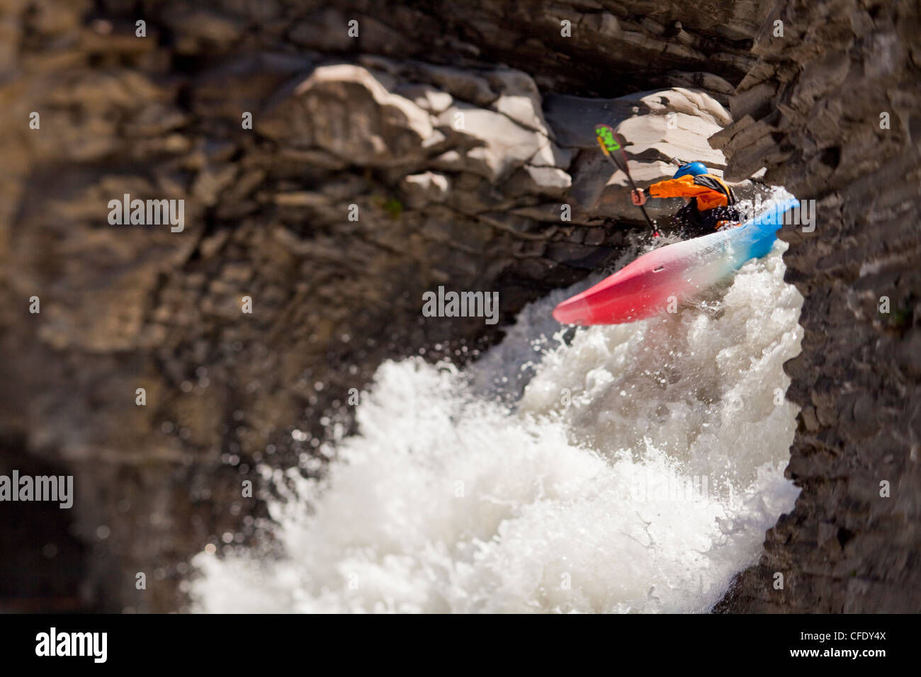 A male whitewater kayaker blasts through a waterfall on the Big Horn ...