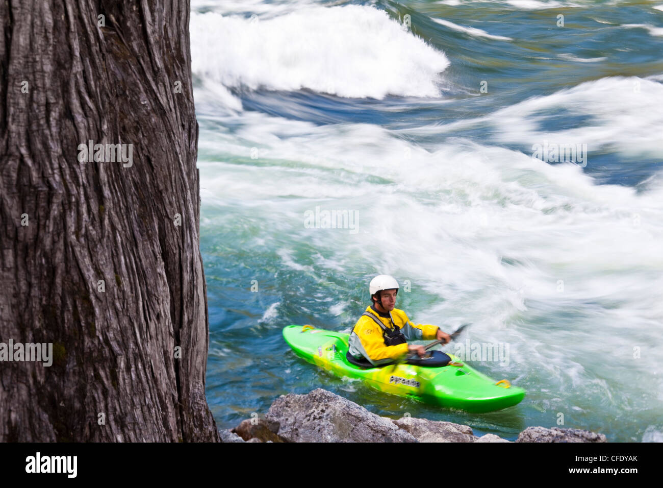 A male kayaker waiting in an eddy before surfing an amazing wave on the ...