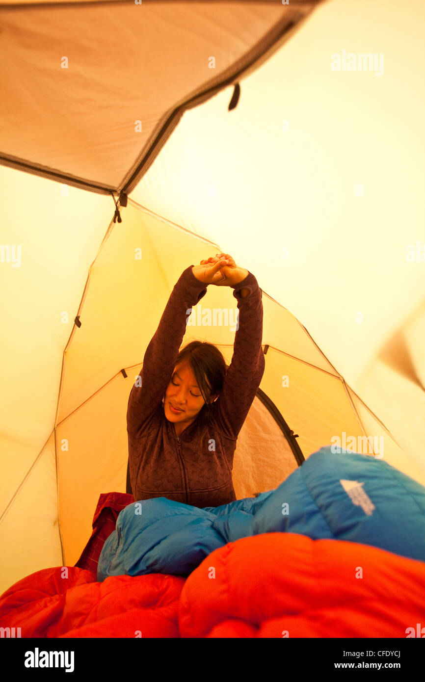 A young woman waking up while camping in Jasper Provincial Park ...
