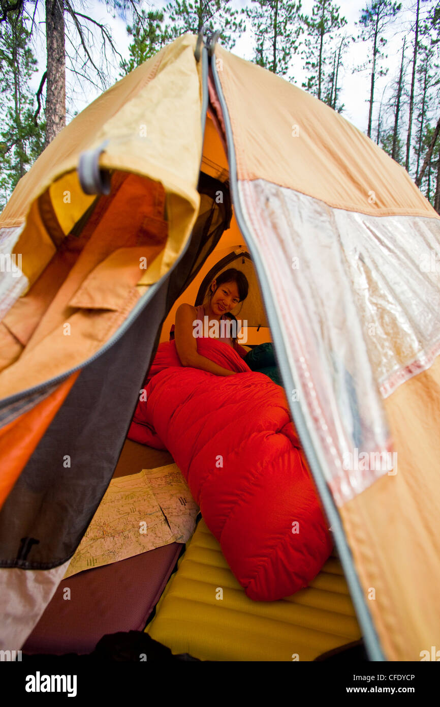 A young woman waking up while camping in Jasper Provincial Park ...