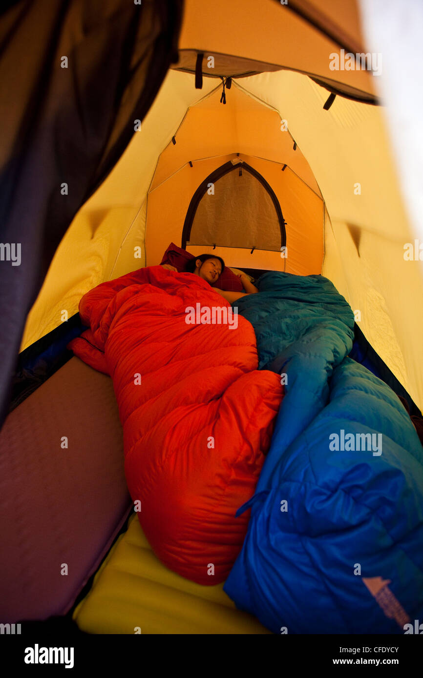 A young woman waking up while camping in Jasper Provincial Park ...