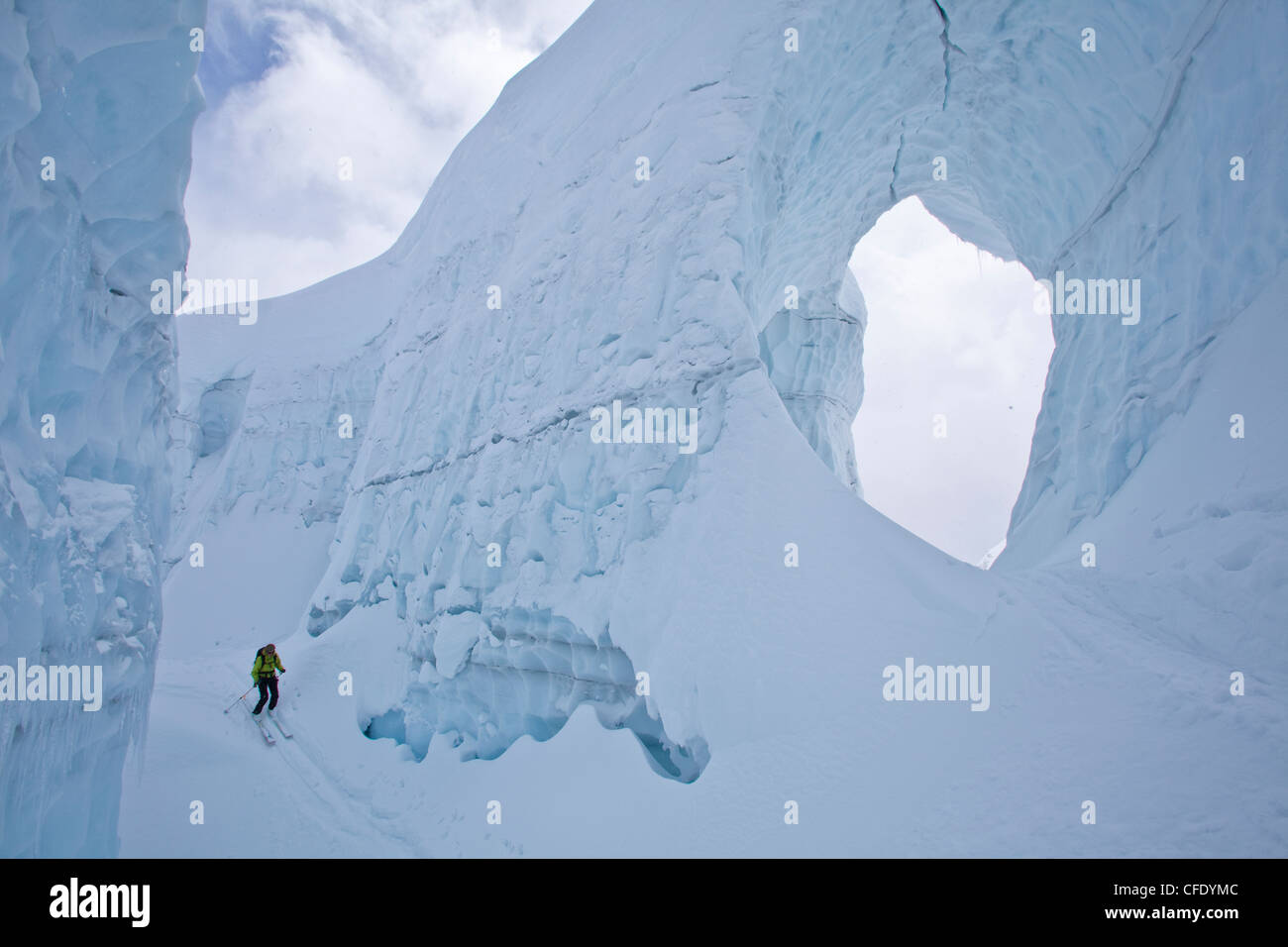 A woman backcountry ski touring through incredible glacier ice. Icefall ...