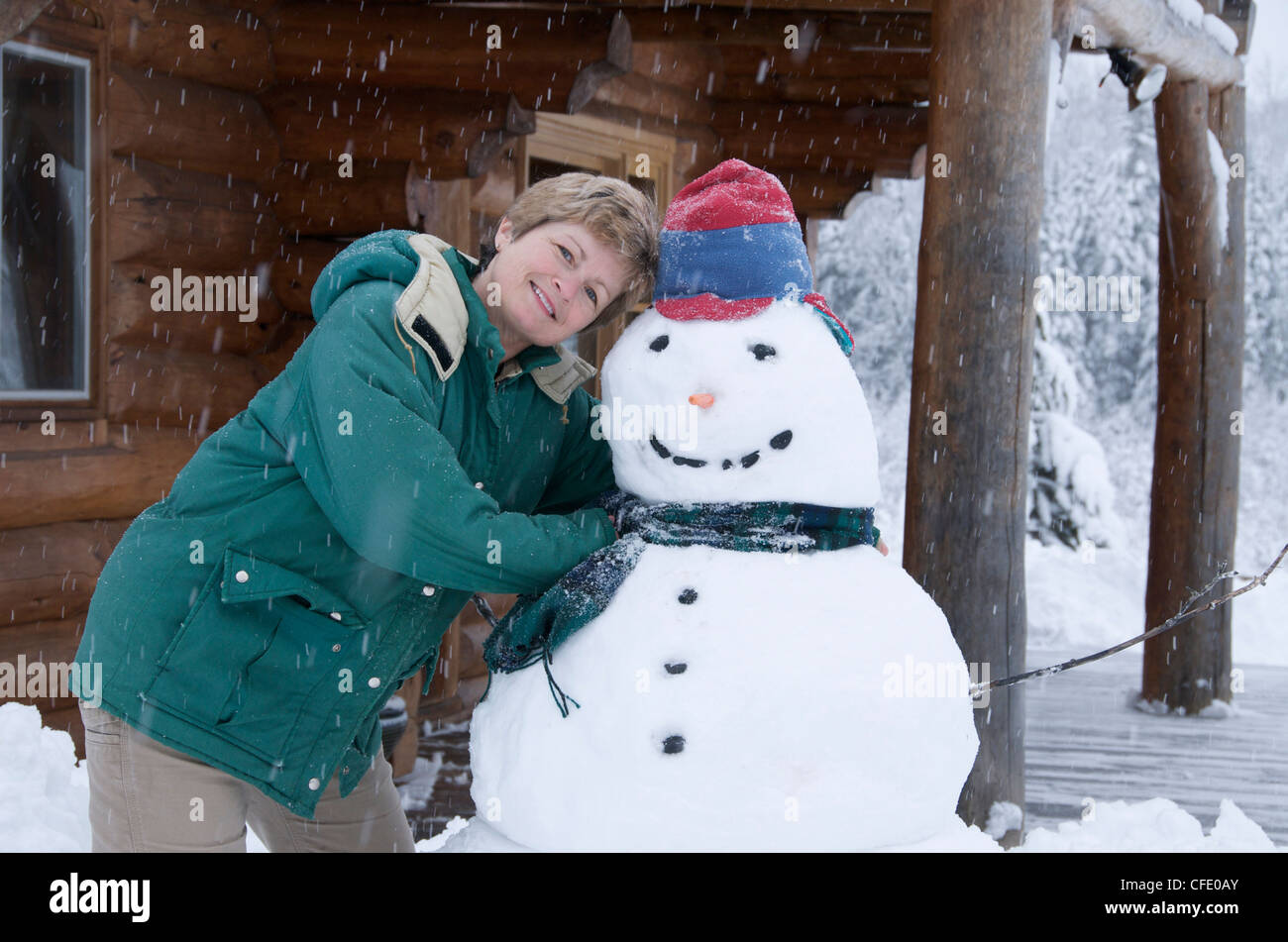 Woman building snowman with snow falling, Ontario, Canada Stock Photo ...