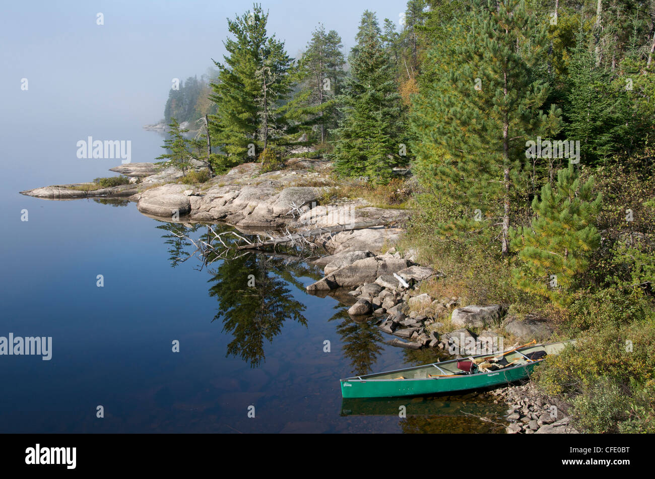 Rocky shoreline of French Lake with beached canoe in Quetico Provincial ...