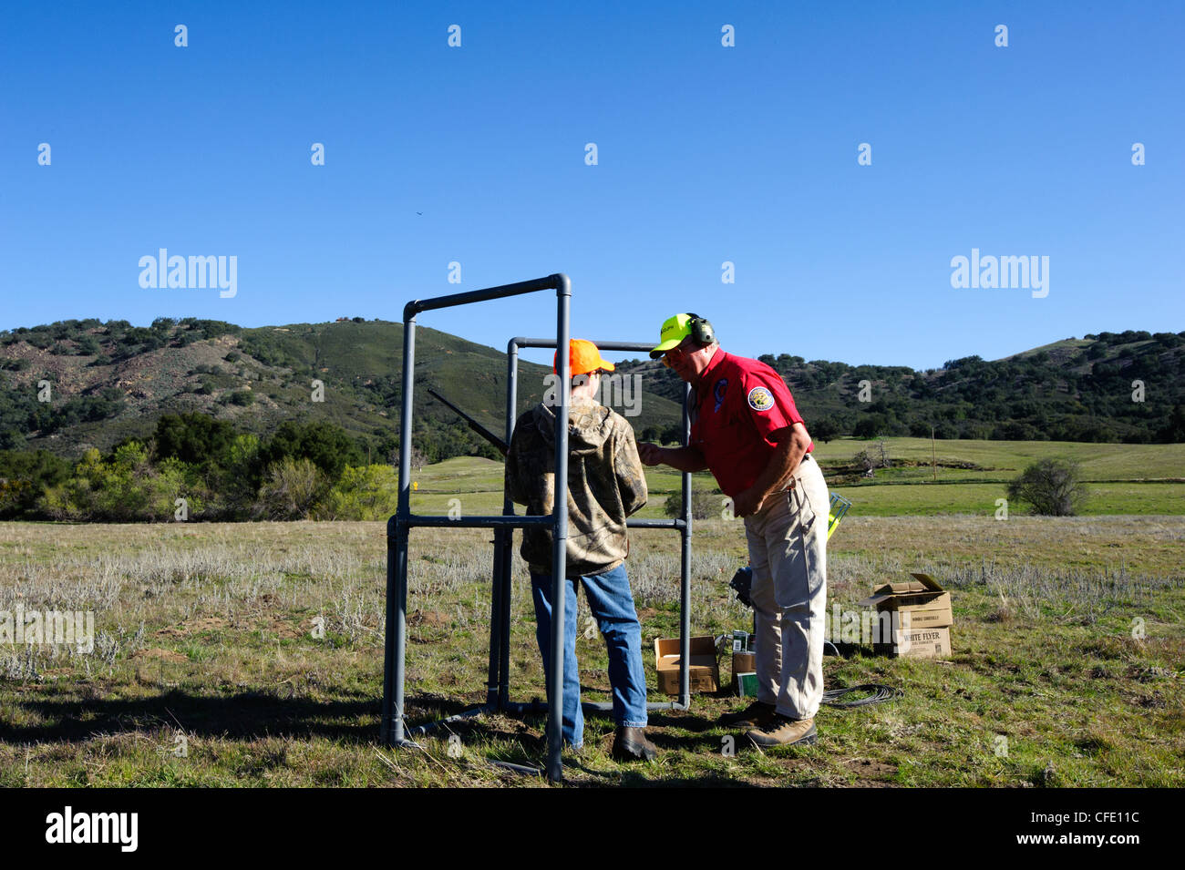 A young hunter receiving shotgun instruction at a clay target range ...
