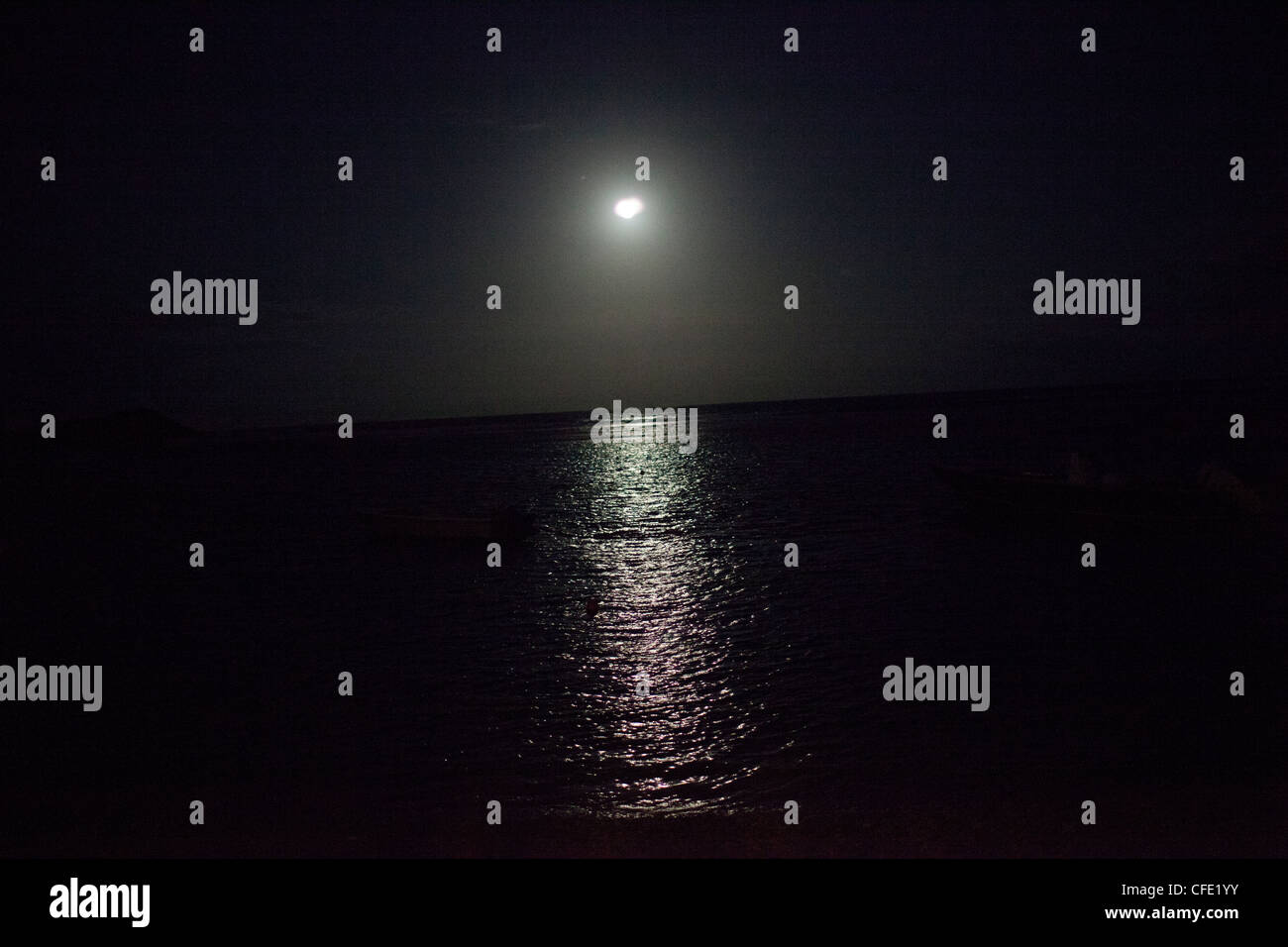 A full moon rises over a bay in Clifton, Union Island, St. Vincent and ...