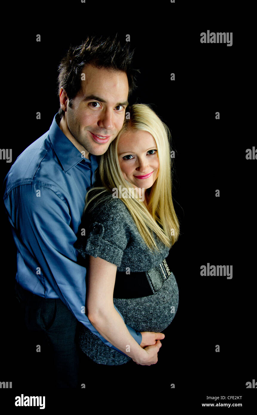A maternity image of a trendy couple, against a low key (black ...