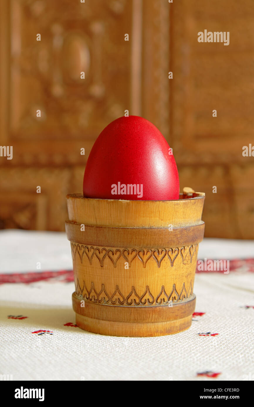 Red Easter egg in a traditional wooden canister with light reflection ...