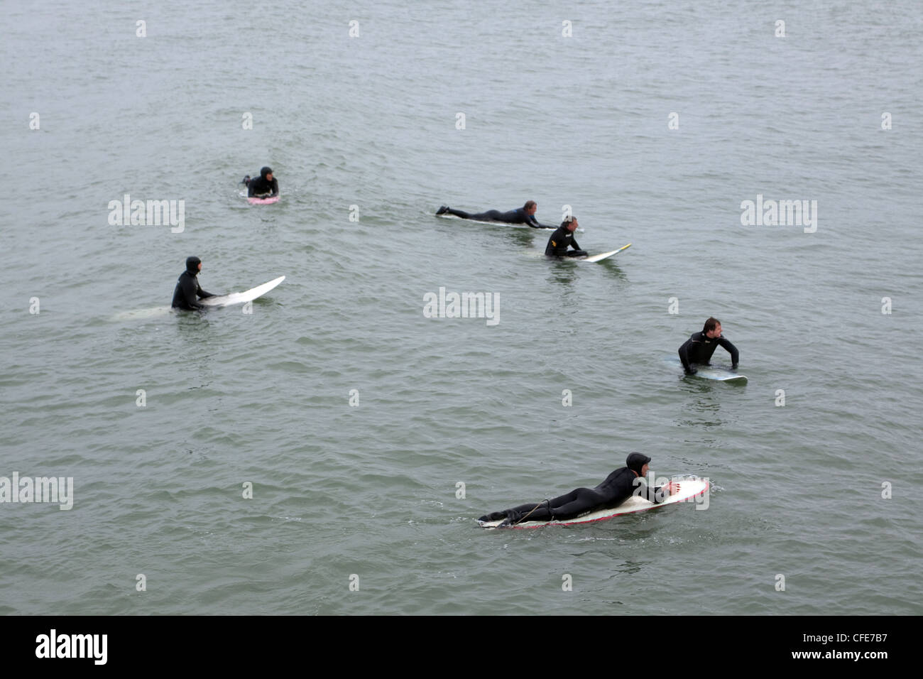 A group of surfers waiting to catch a wave next to Bournemouth Pier ...