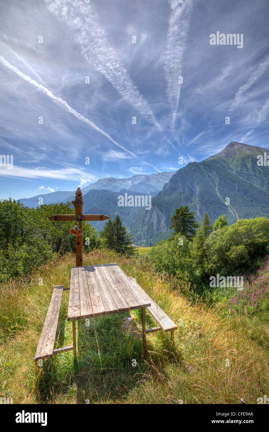 Vertical oriented image of wooden cross on the bench at alpine meadow ...