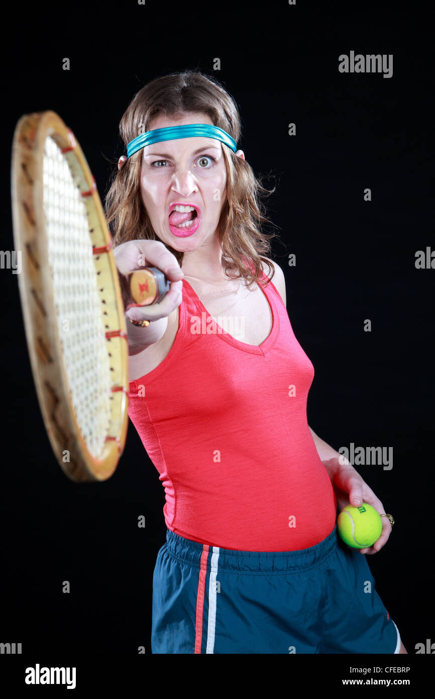 Goofy retro athlete holds tennis racket toward camera while making a ...