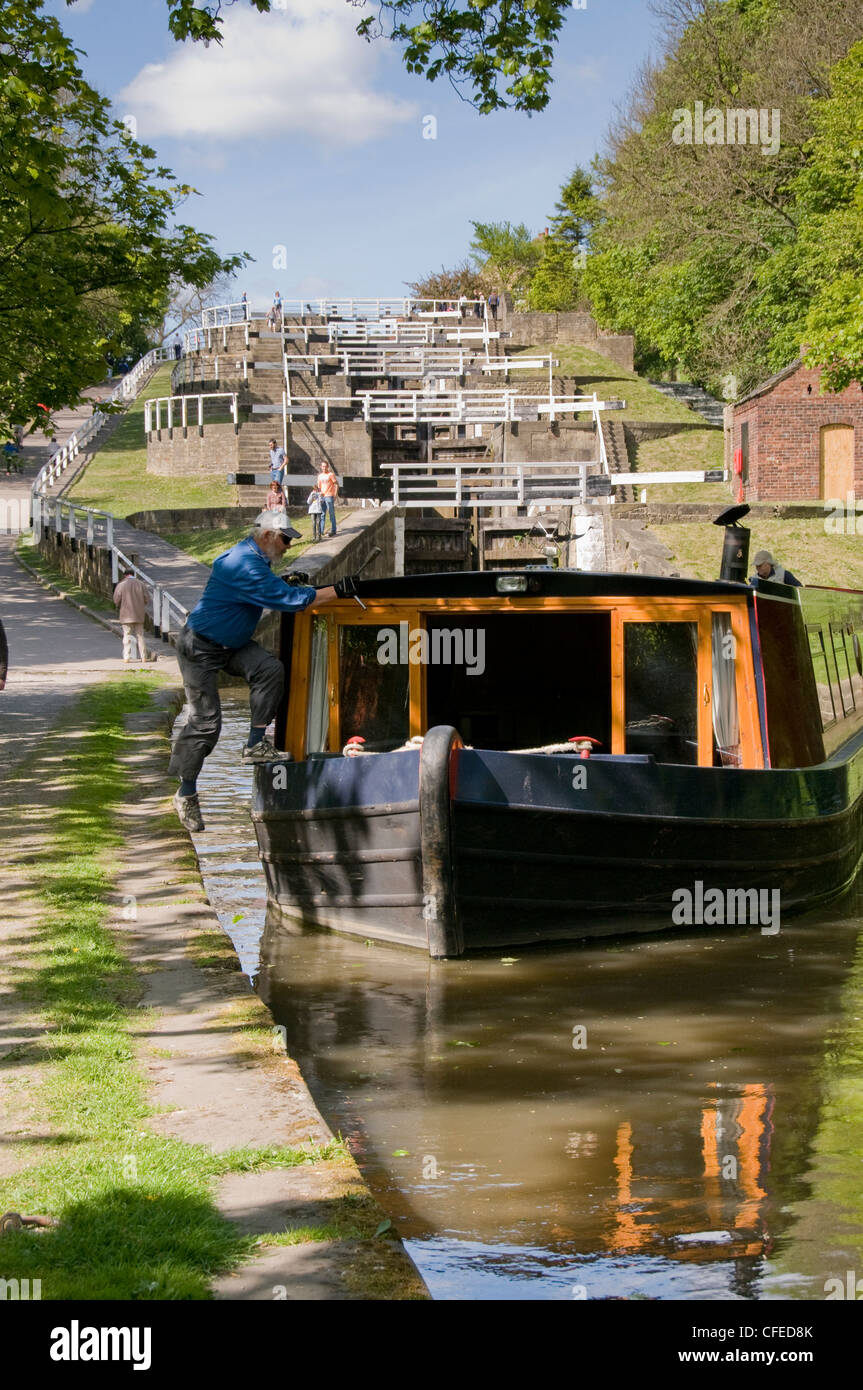 Man jumping on board narrowboat from towpath, after travelling through ...