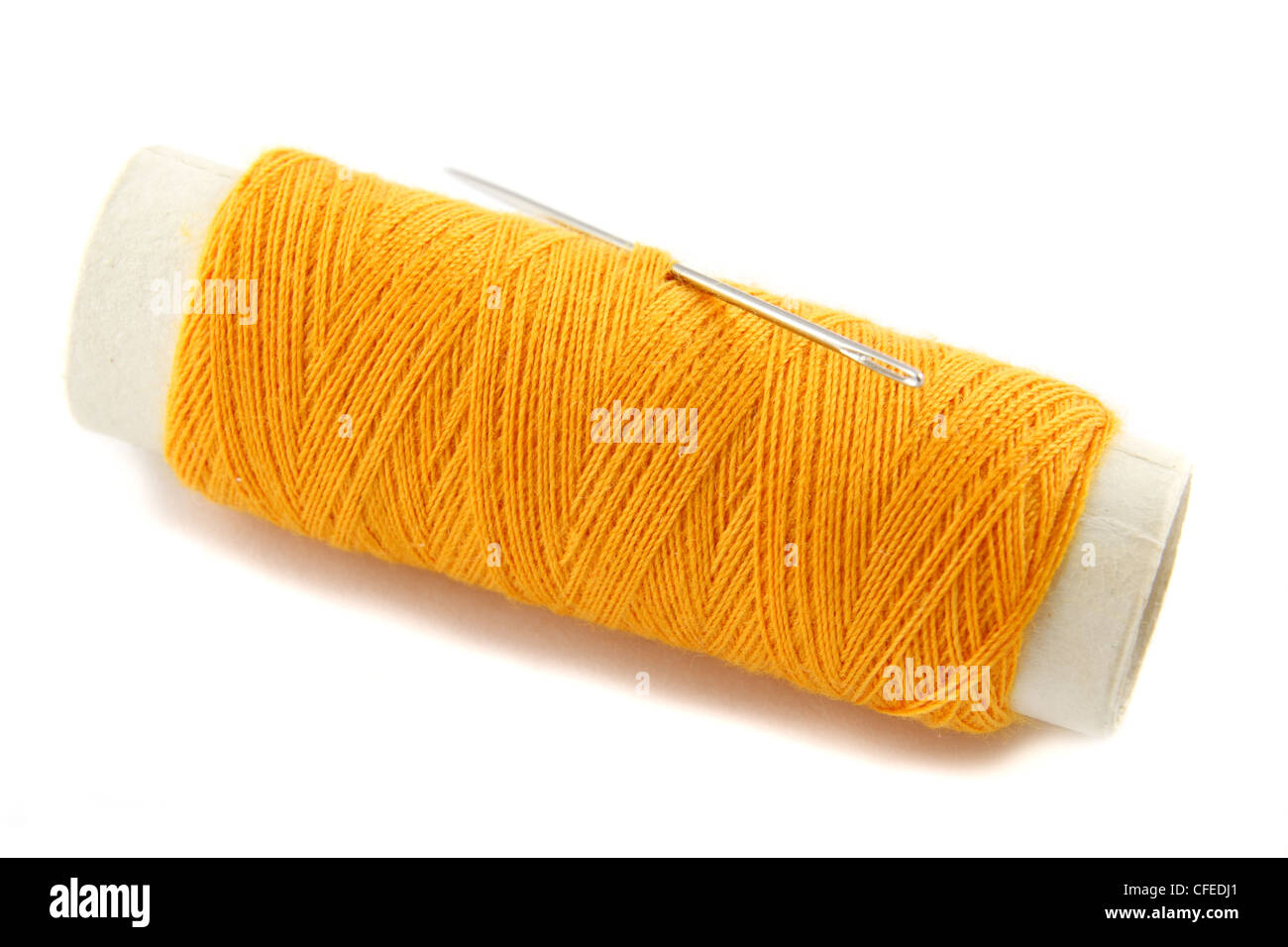 Orange thread bobbin with needle on white background Stock Photo - Alamy