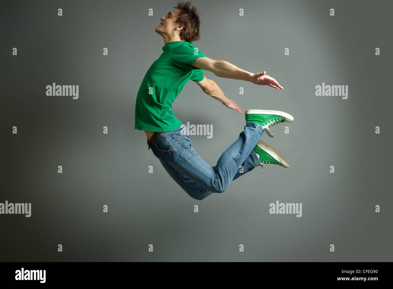 Smiling guy jumping high holding hands behind Stock Photo - Alamy