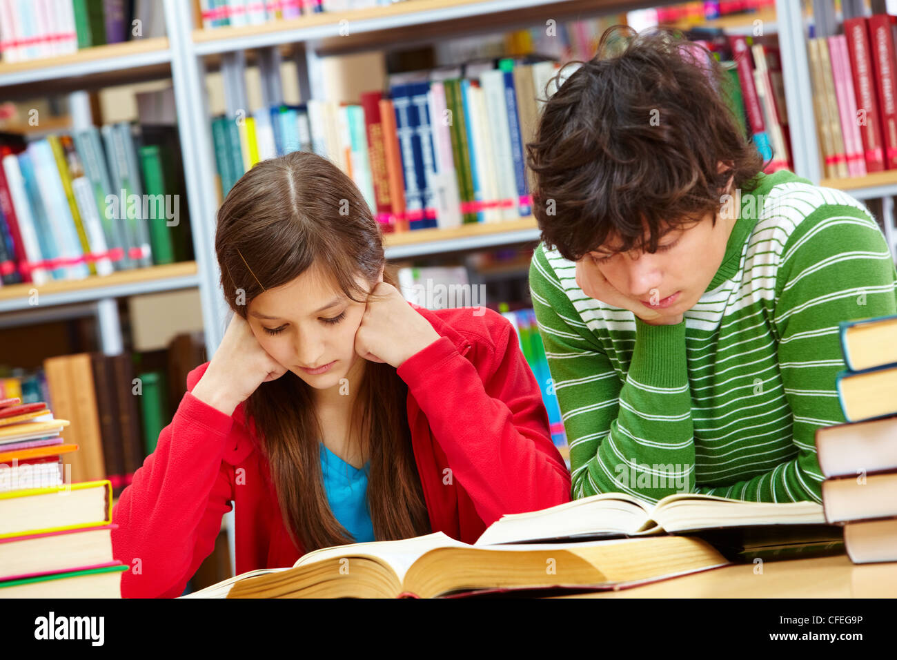 Serious boy and girl reading books at library Stock Photo - Alamy