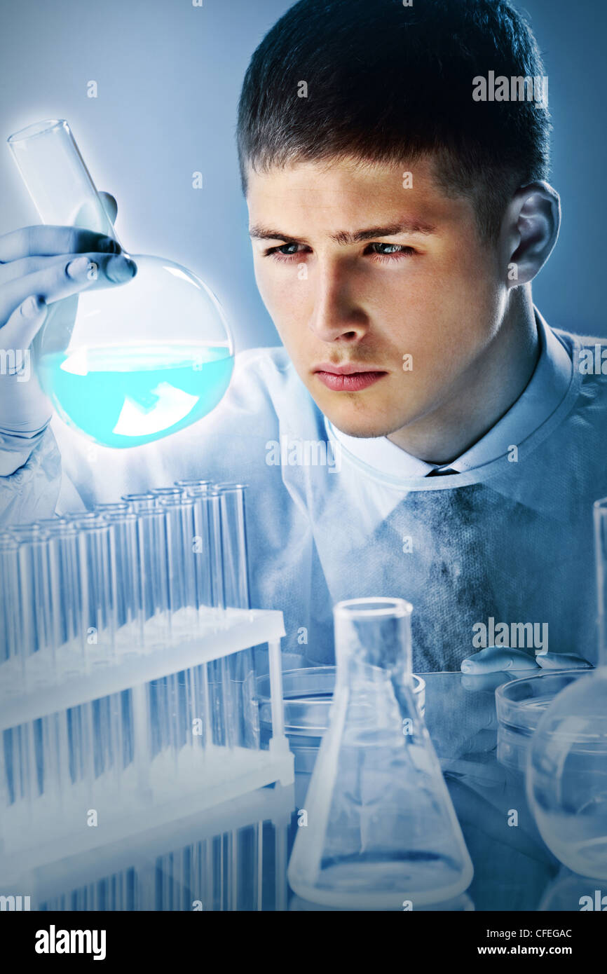 Serious young man in gloves holding a beaker with liquid sample Stock ...