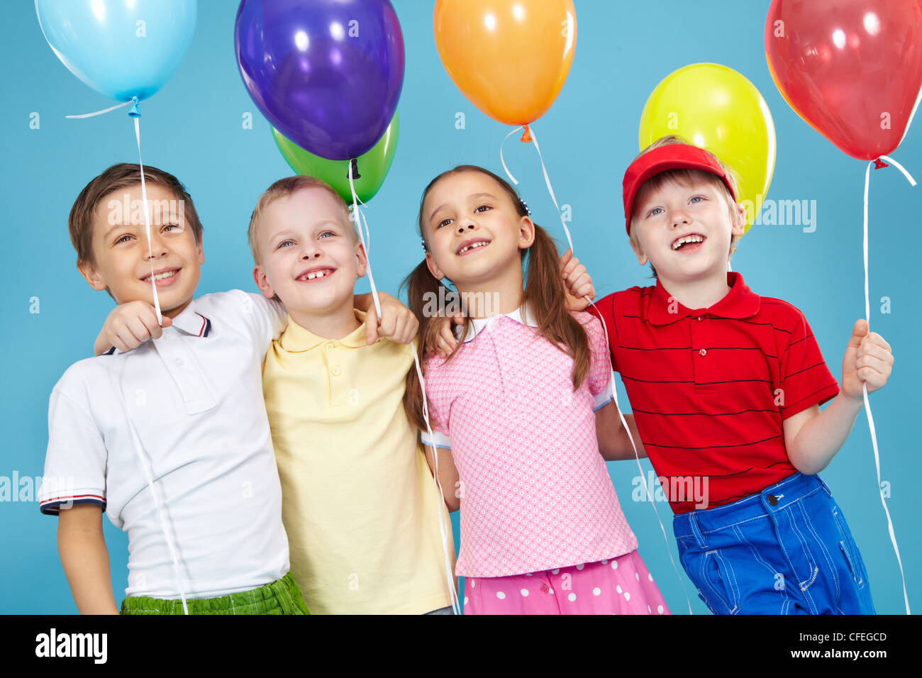 Smiling children looking at something off-screen, each one holding a ...