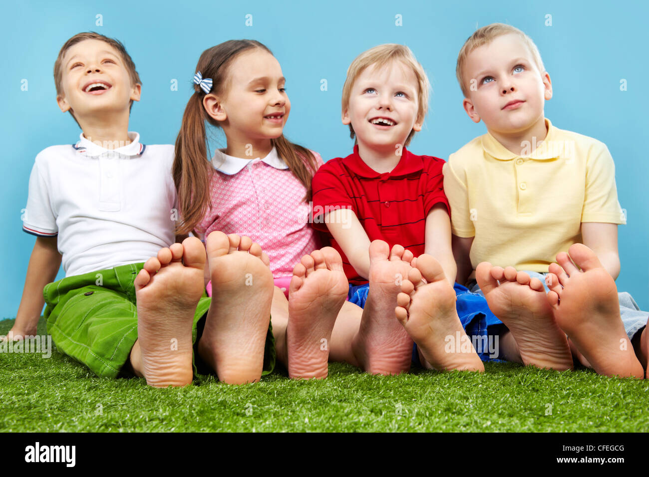 Happy children sitting on the lawn barefoot Stock Photo - Alamy