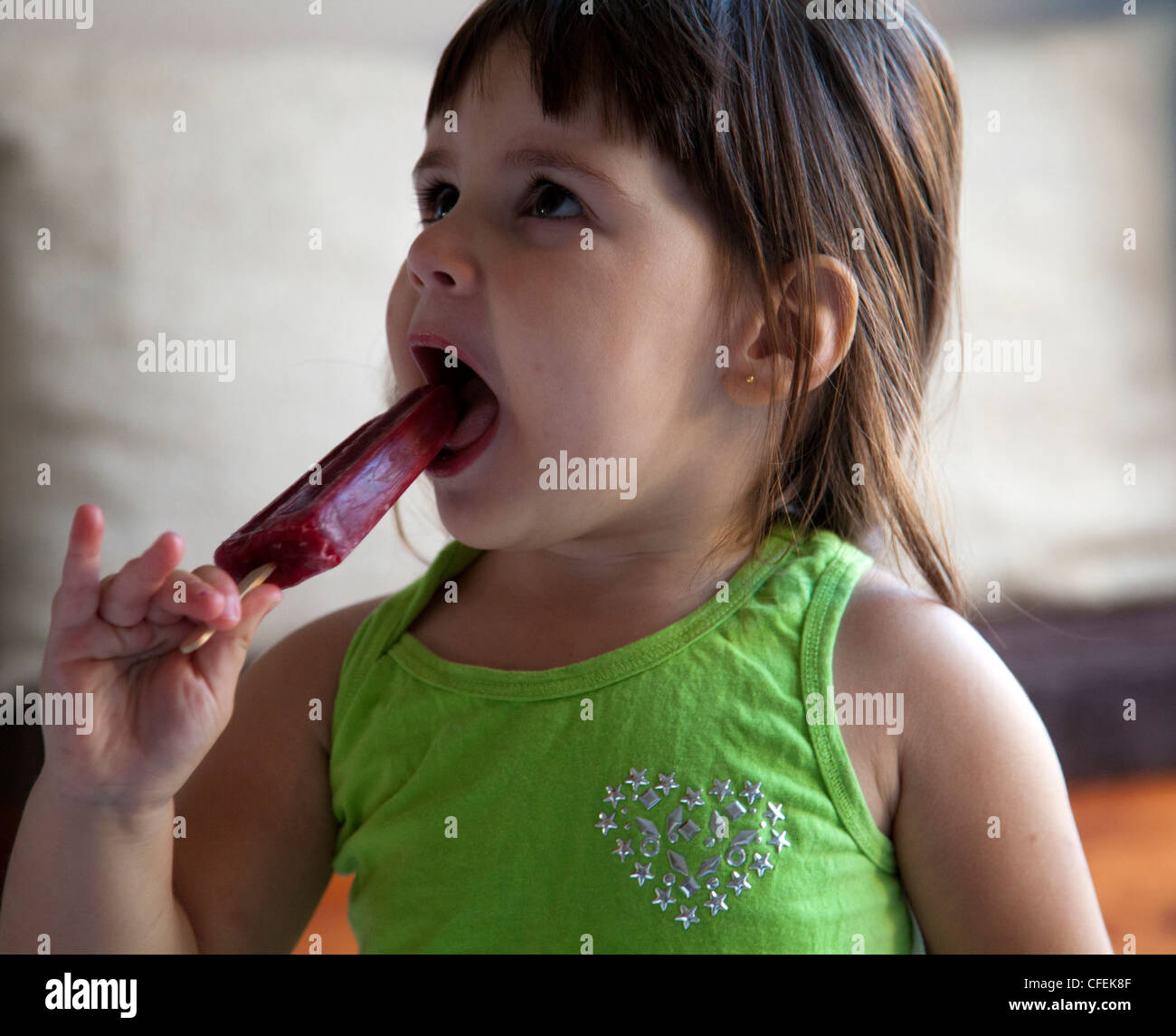 Girl enjoying red ice lolly Stock Photo - Alamy
