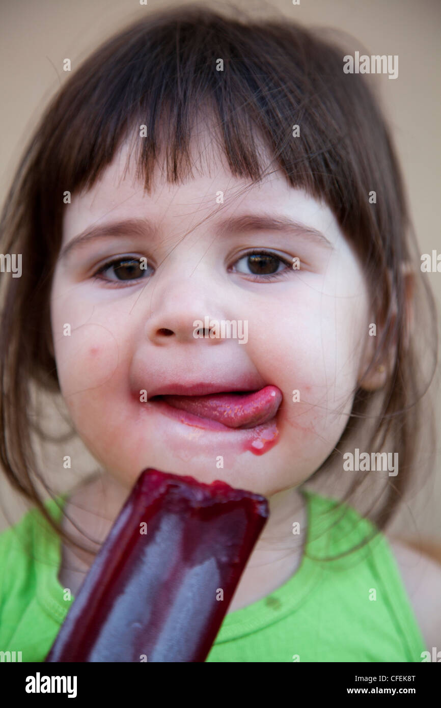 Girl enjoying red ice lolly Stock Photo - Alamy