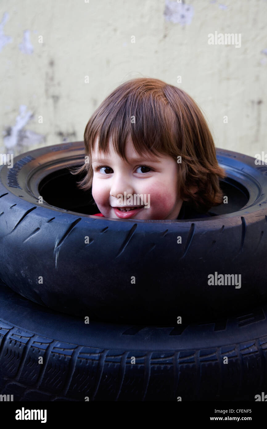 Three year old boy playing in stack of tyres Stock Photo - Alamy