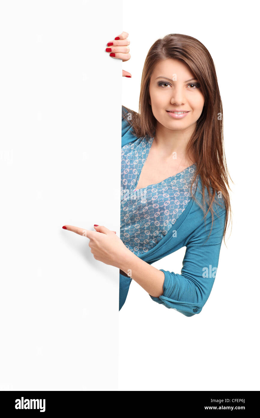 A smiling beautiful girl pointing on a white panel isolated on white ...
