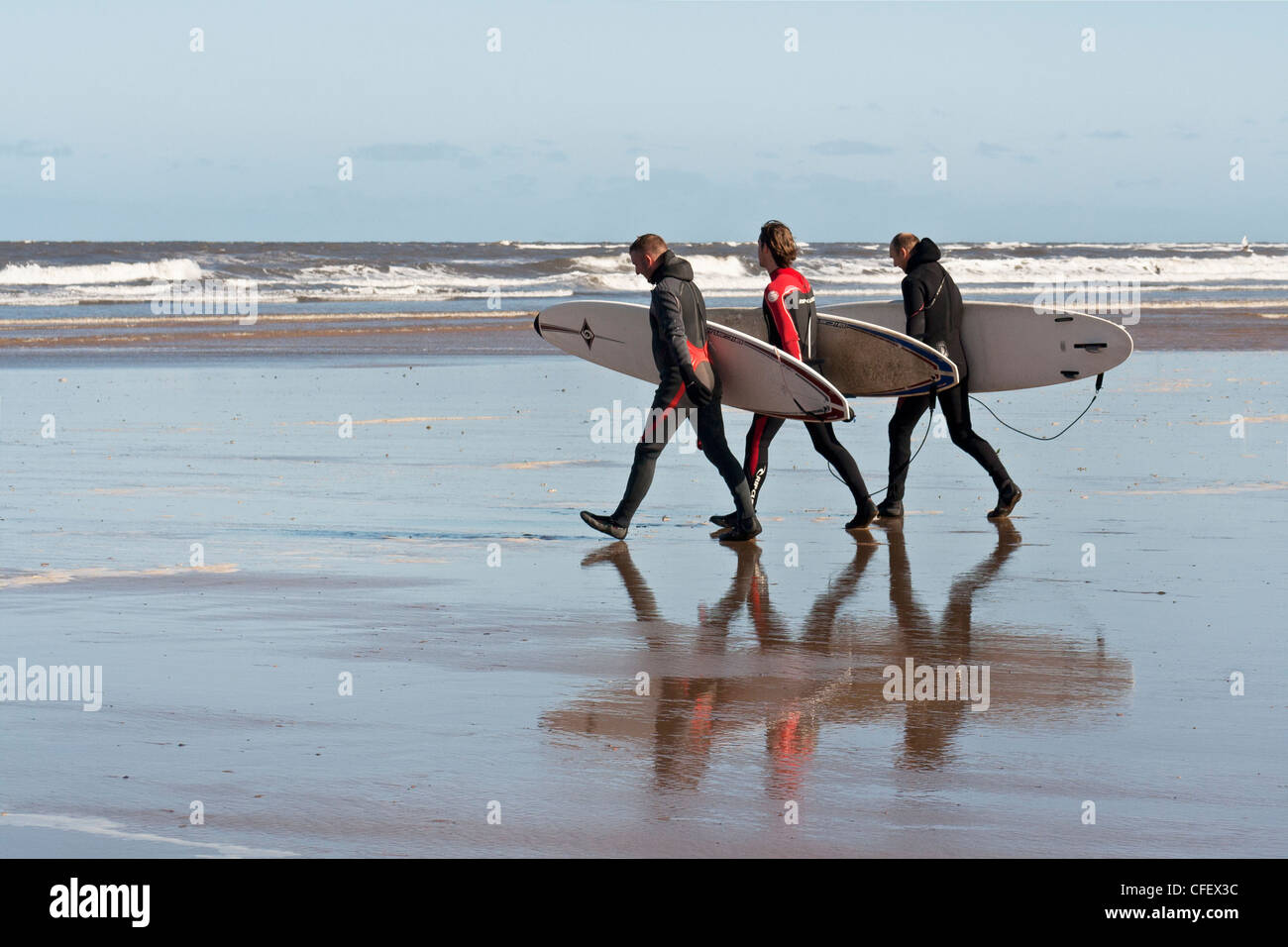 Three surfers heading for the sea Stock Photo - Alamy