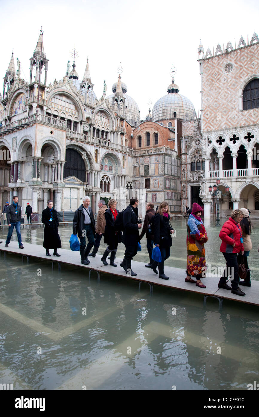 Tourists walking on footbridges during high tide in St. Mark's Square ...