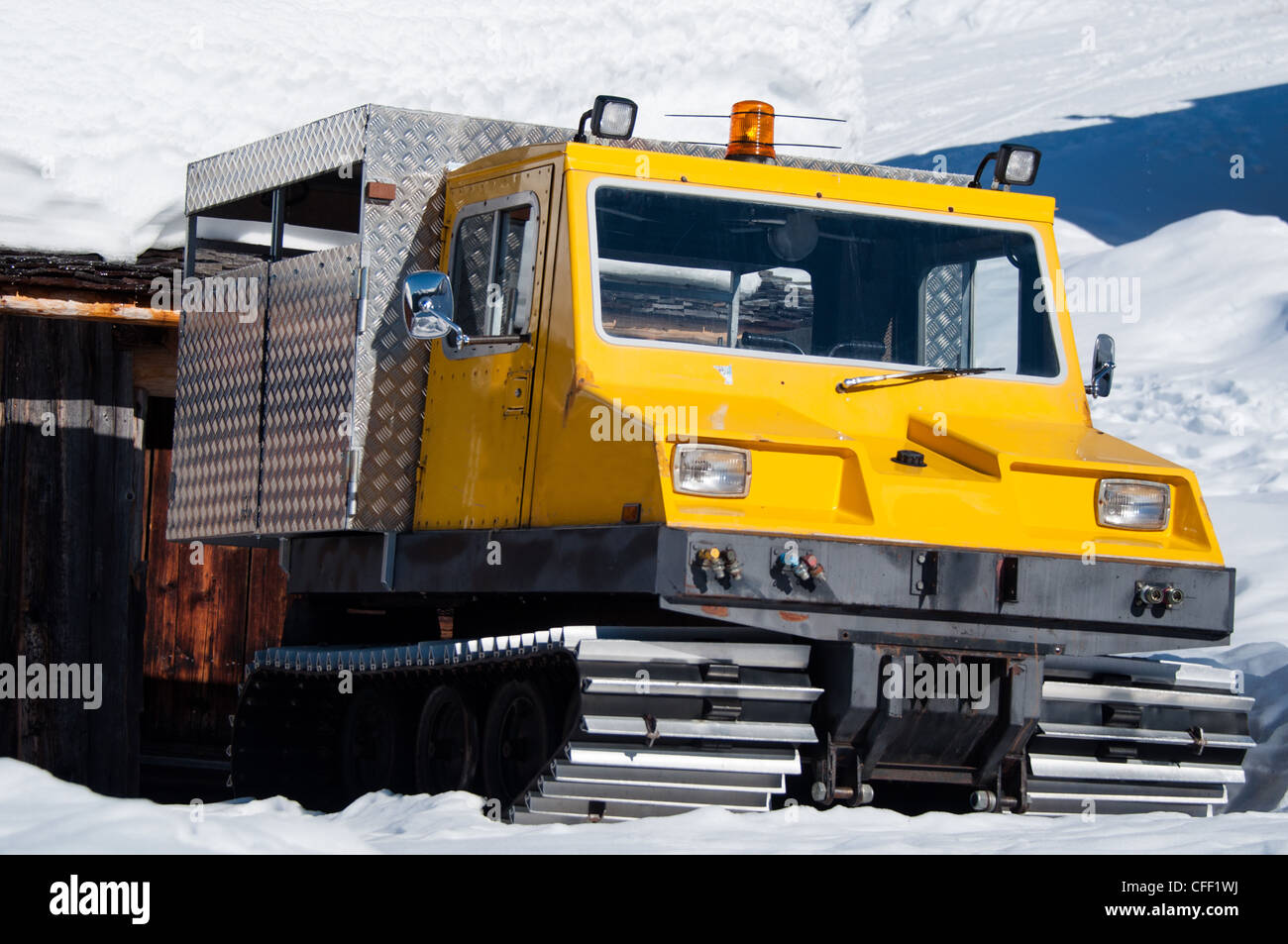 Old snow groomer / snowcat functioning as transporter standing nearby ...