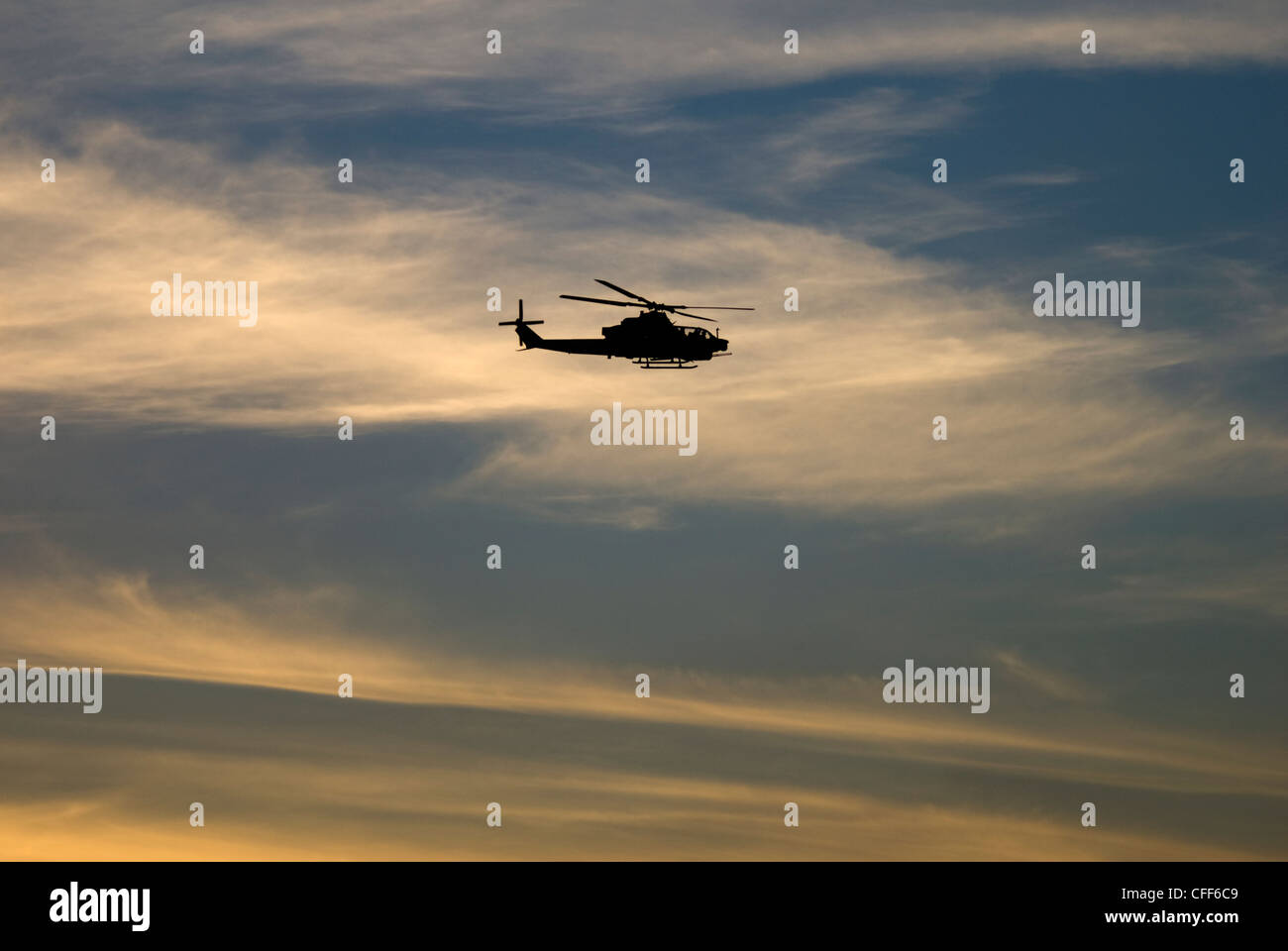 Apache attack helicopter flying over the Pacific Ocean at sunset in San ...