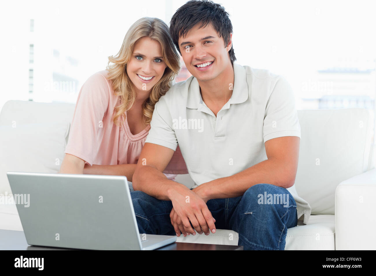 Man and woman sitting beside each other, smiling as they look straight ...