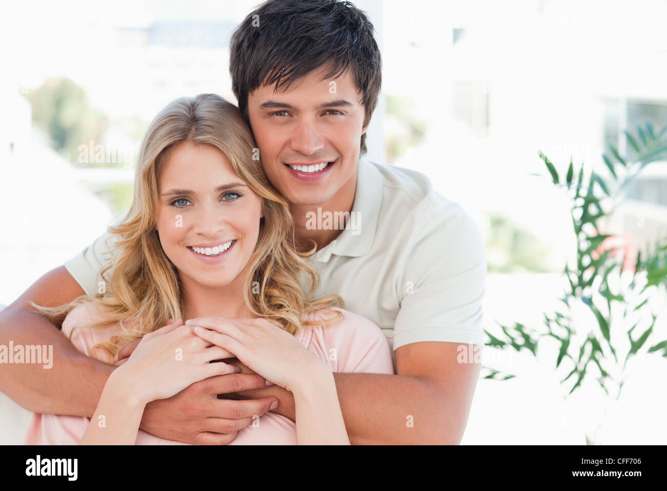 Man and woman hold hands while hugging and smile while looking forward ...