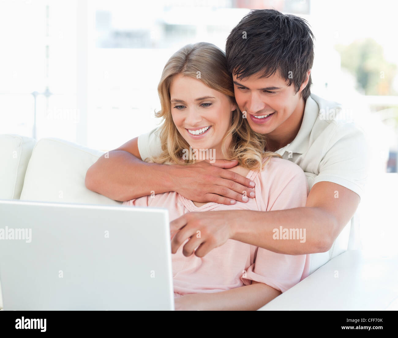 Man and woman hugging, as they watch the laptop Stock Photo - Alamy