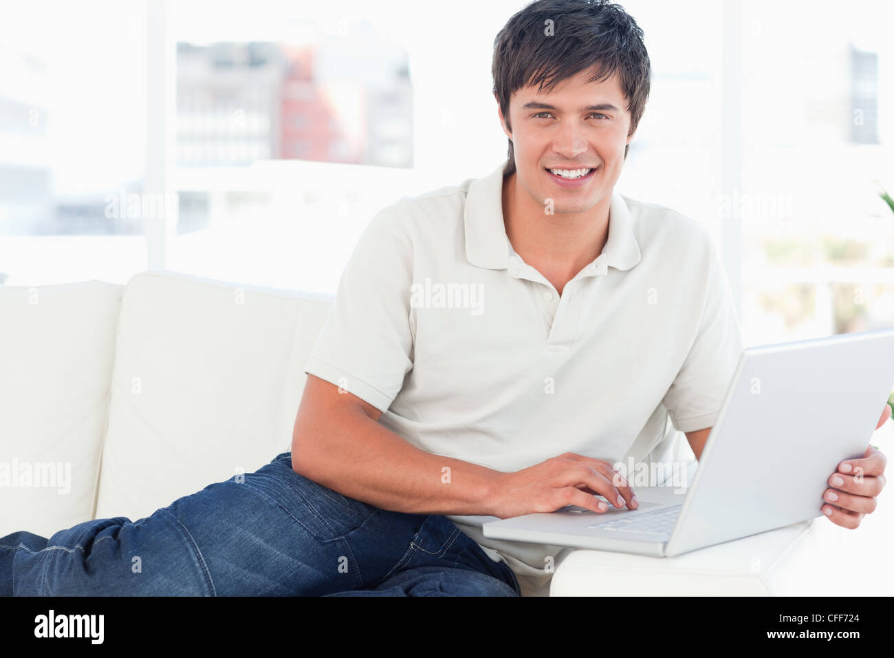 Man sitting across the couch by the table with his laptop and smiling ...
