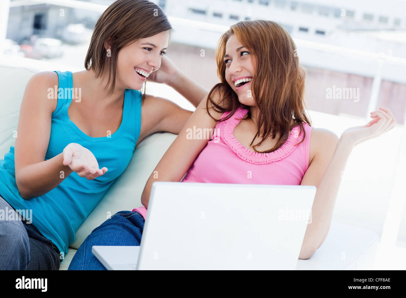 Two friends sitting on a sofa while talking about the laptop Stock ...
