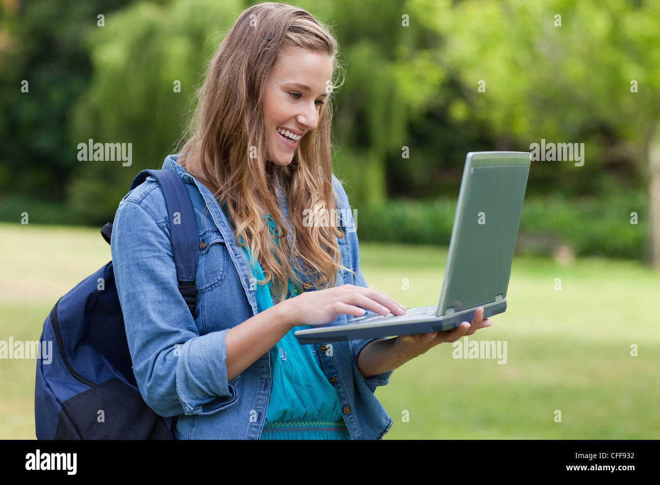 Smiling teenage girl using her laptop while standing upright Stock ...