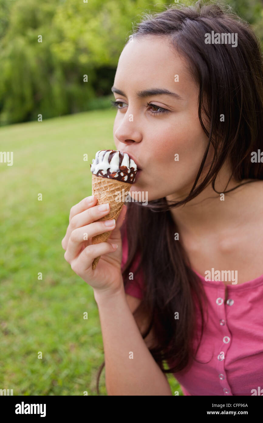 Young attractive girl eating a cone while standing in a park Stock ...
