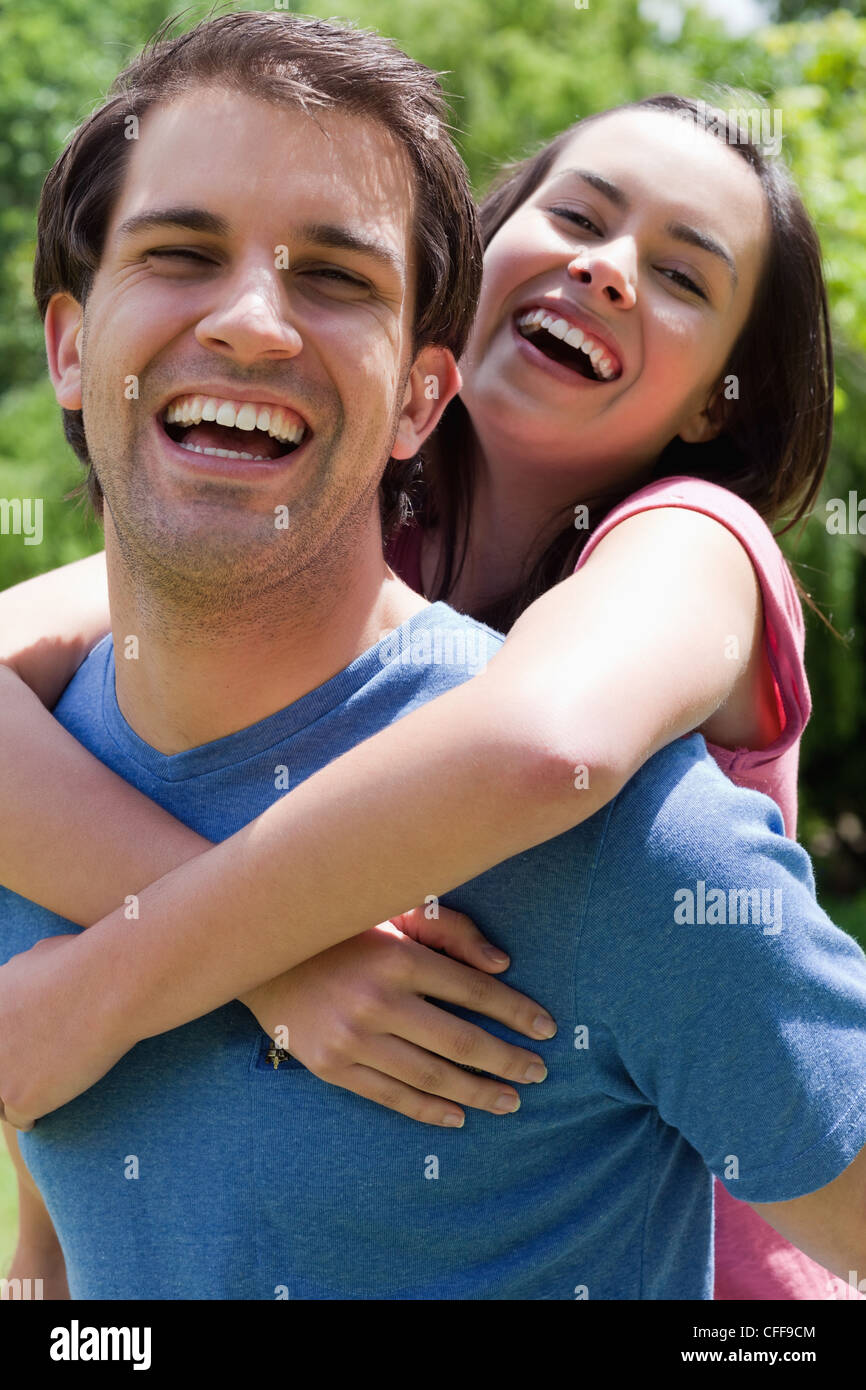Young smiling woman standing in a park with her arms wrapped around her ...