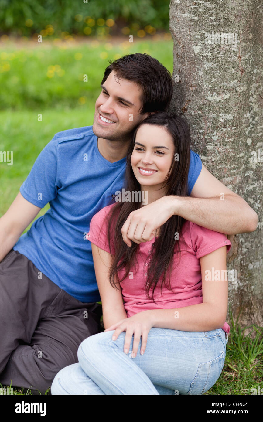 Young man placing his arm around his girlfriend while leaning against a ...