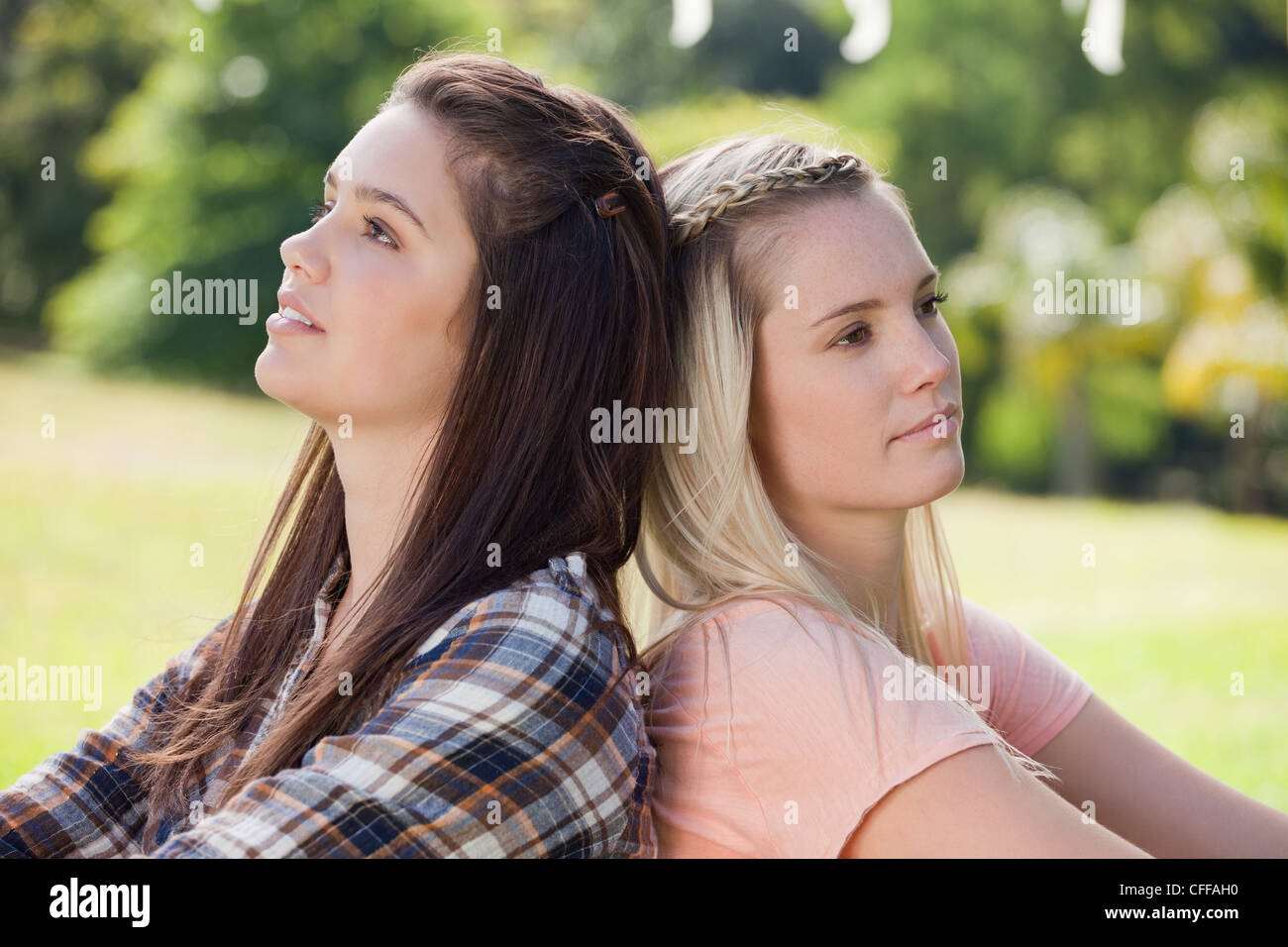 Young serious girls standing back to back Stock Photo - Alamy