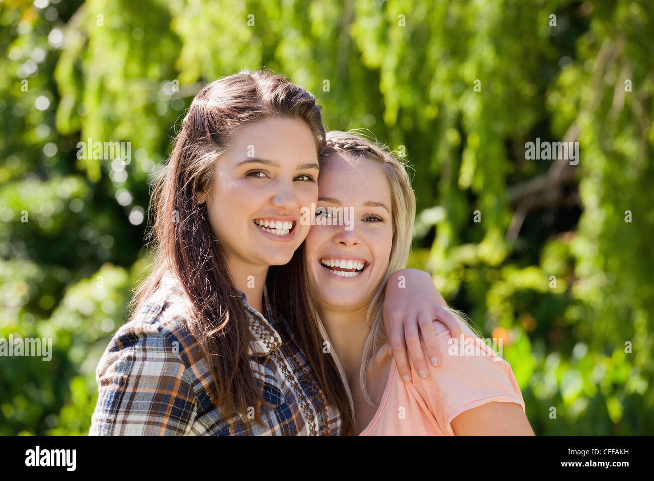 Young smiling girl placing her arm around her friend Stock Photo - Alamy