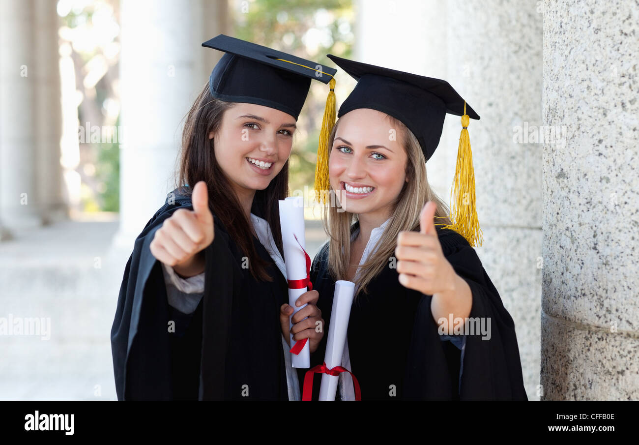 Smiling graduating students putting their thumbs up Stock Photo - Alamy