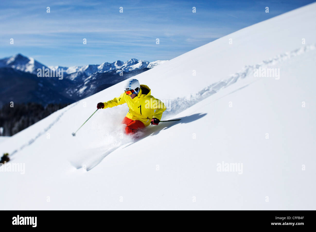 A athletic skier rips fresh powder turns on a sunny day in Colorado ...