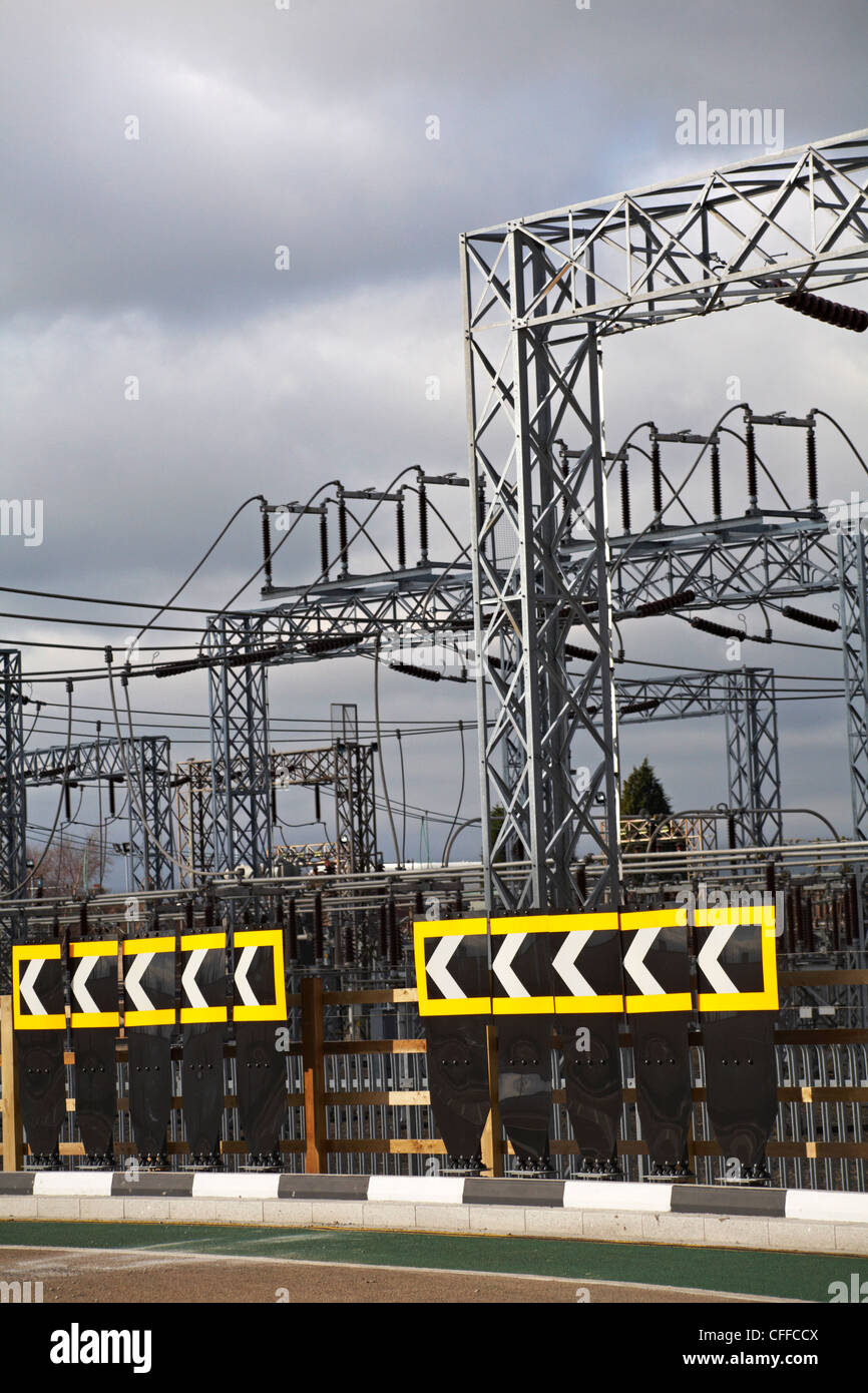electricity grid with sharp bend road signs under grey skies at ...
