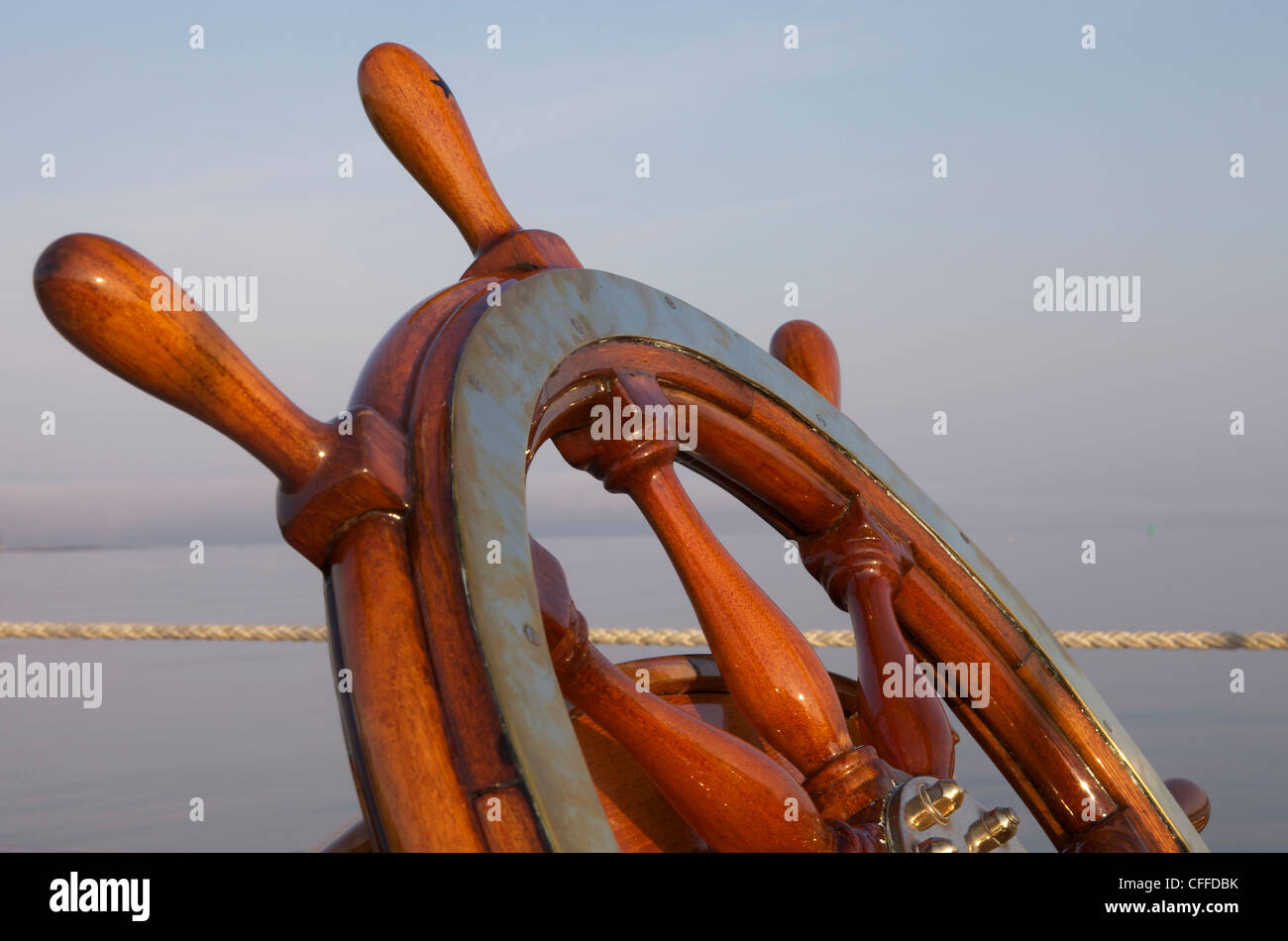 A warm glow highlights the ship's wheel on board a classic sailing ...