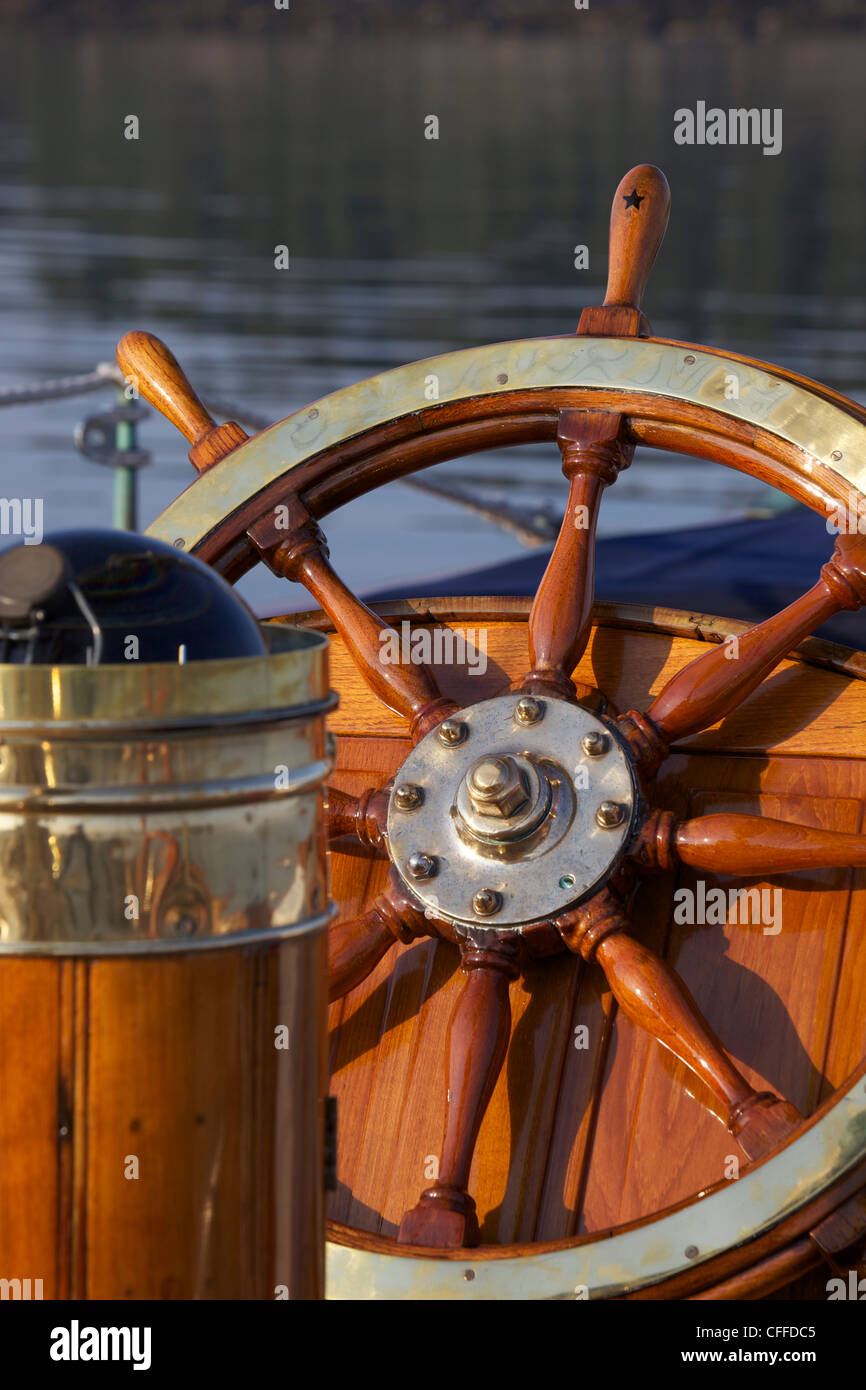A warm glow highlights the ship's wheel and compass on board a classic ...