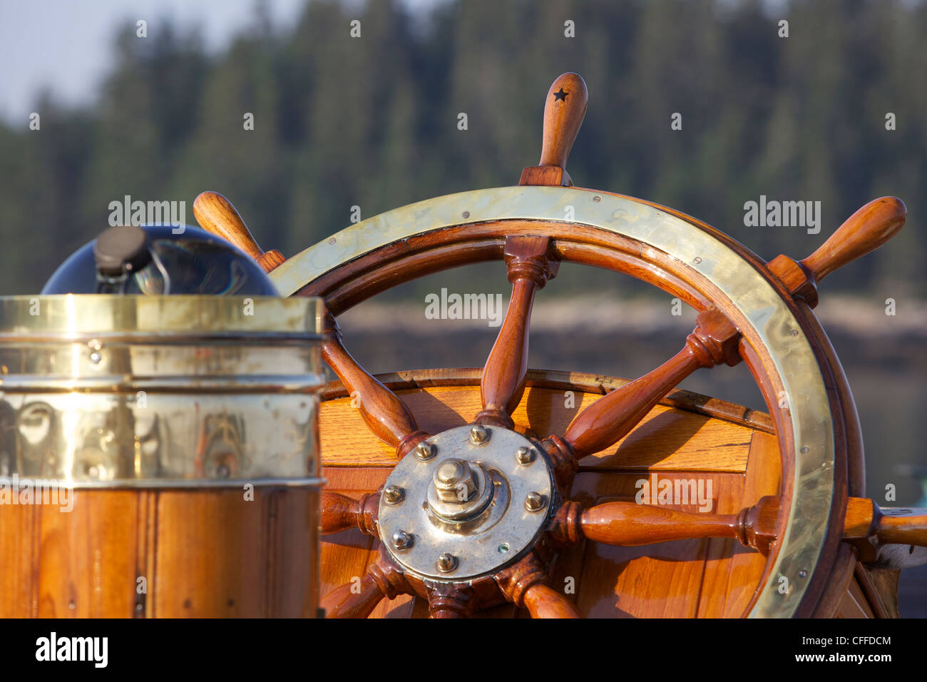 A warm glow highlights the ship's wheel and compass on board a classic ...