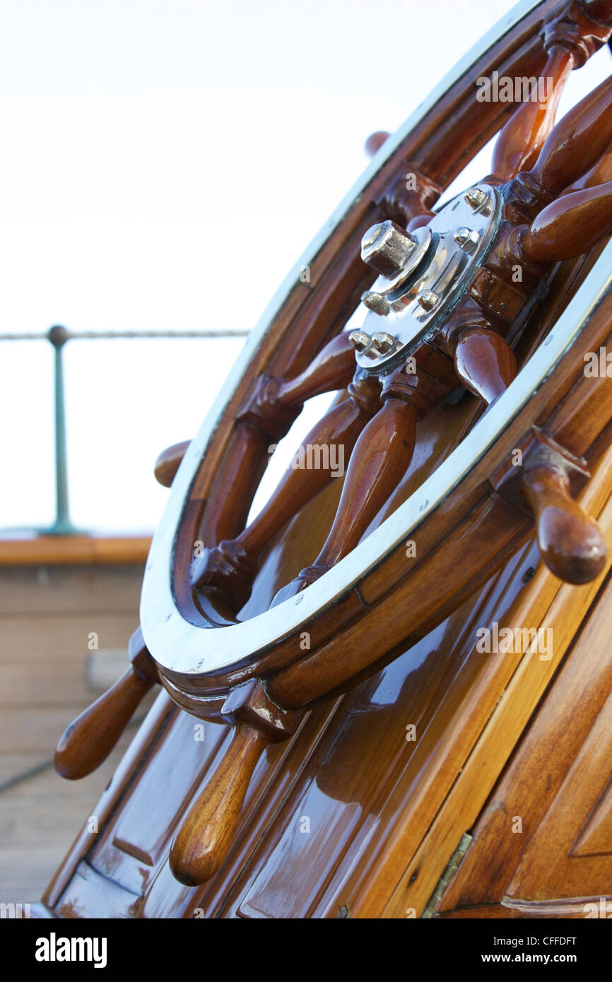 A warm glow highlights the ship's wheel on board a classic sailing ...